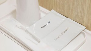 Uma bancada de banheiro com um dosador de sabonete branco, uma embalagem de sabonete líquido e uma embalagem de shampoo.