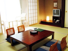 Um quarto japonês tradicional, com tatames, uma mesa de madeira baixa e cadeiras de madeira.