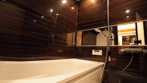 Uma casa de banho moderna com uma banheira grande, cabine de duche em vidro e um espelho a refletir o espaço.
