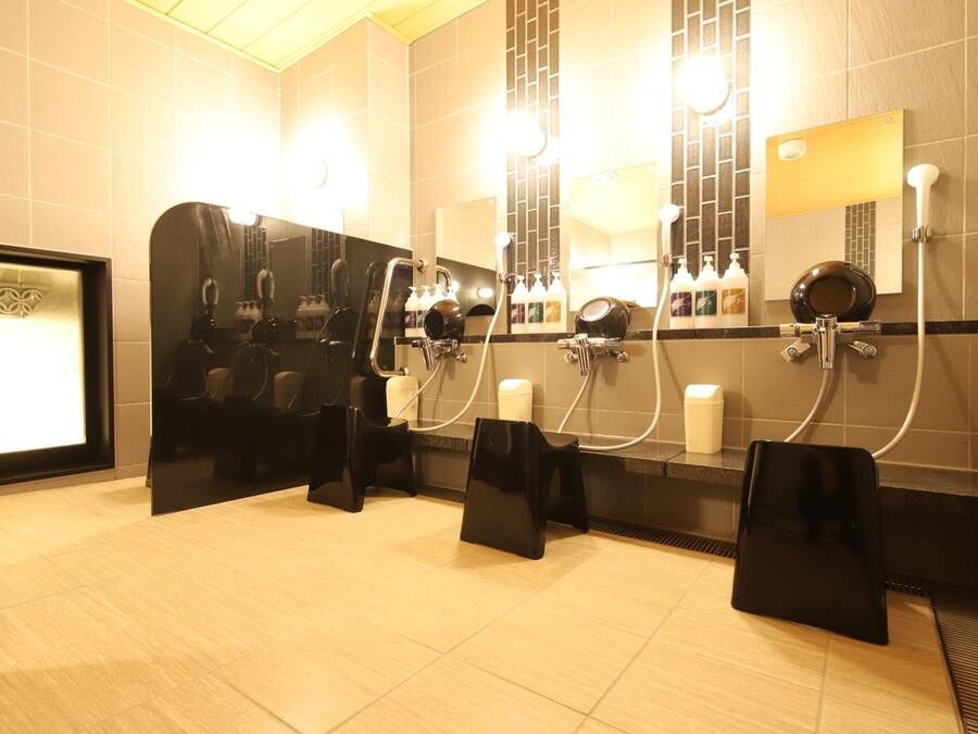 Casa de banho de hotel com várias pias, espelhos e secadores de cabelo.