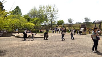 Um parque com parquinho, bancos e um caminho de terra.