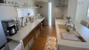Uma cozinha moderna com bancadas brancas, cafeteira, micro-ondas e pia.