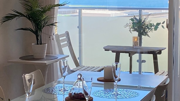 Varanda com mesa posta para dois, com vista para o litoral.