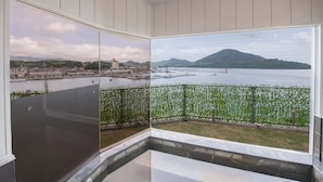 Uma varanda com vista para um porto, uma montanha e o horizonte da cidade.