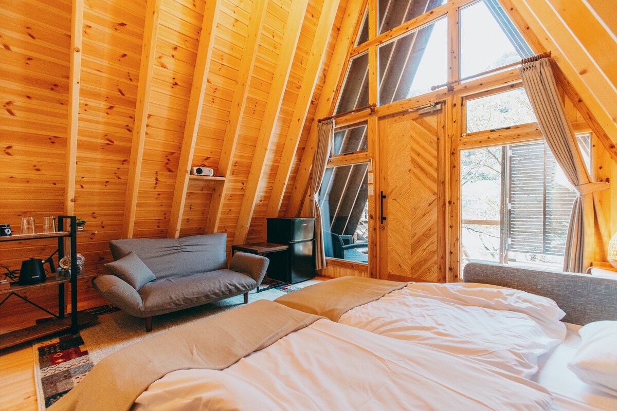 Um quarto aconchegante com teto inclinado, uma cama, um sofá e uma televisão.