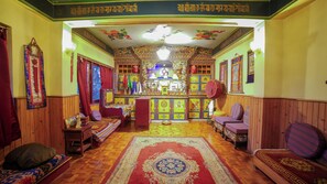 Quarto tradicional com uma roda de oração, um pequeno altar e decorações coloridas.