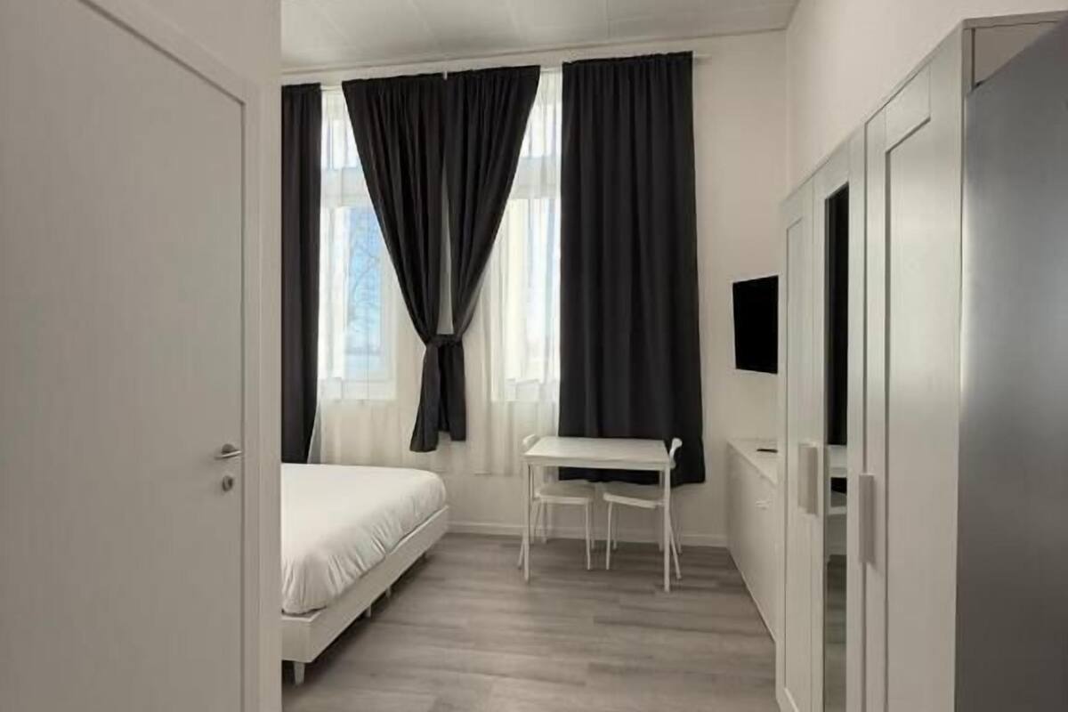 Quarto de hotel moderno com uma cama, uma escrivaninha e um guarda-roupa.