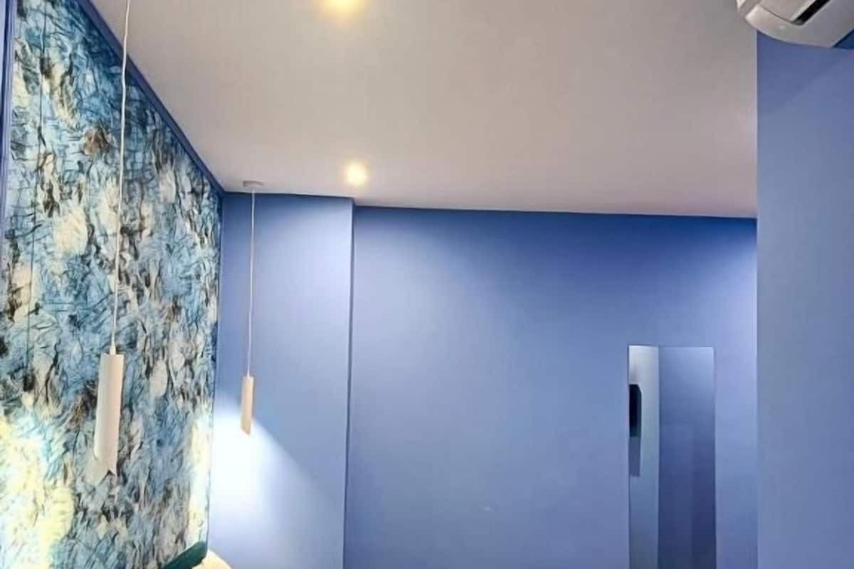 Quarto com uma cama, ar condicionado fixado na parede e uma luminária de teto.