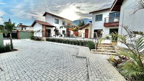 Um bairro residencial com ruas pavimentadas, casas modernas e plantas tropicais.
