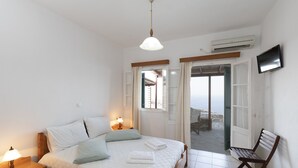 Quarto com cama, mesa de cabeceira, luminária e televisão na parede.