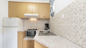 Cozinha compacta com armários de madeira, forno embutido, pia e geladeira.