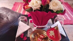 Quarto bem arrumado com uma cama, uma mesa com um vaso de flores, um prato decorativo e uma pequena tigela.