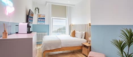Quarto com cama, mesa de cabeceira e janela com vista.