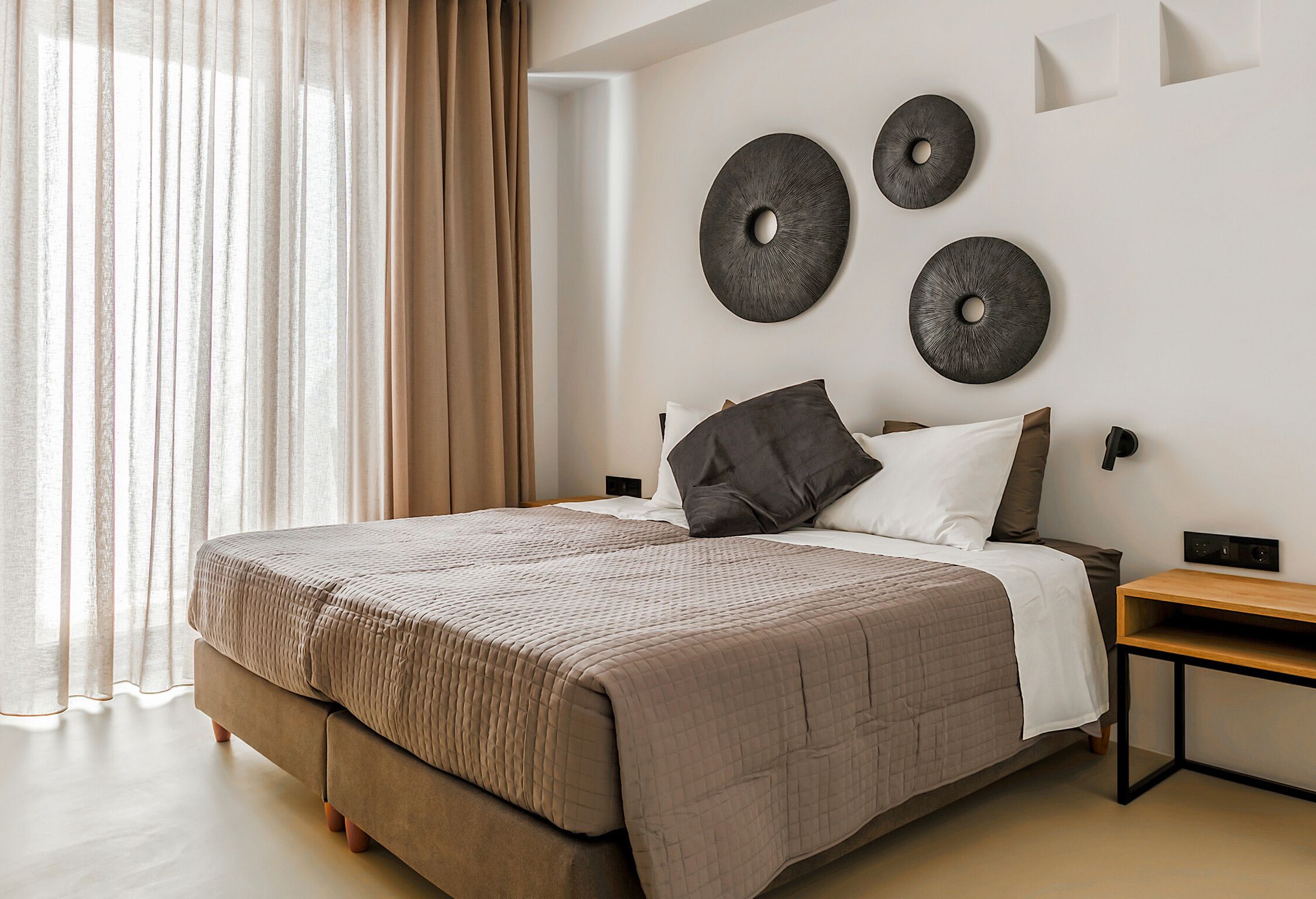 Quarto moderno com uma cama grande, uma mesinha de cabeceira e decoração na parede.