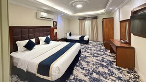 Quarto de hotel com duas camas, televisão, escrivaninha e uma janela grande com cortinas.
