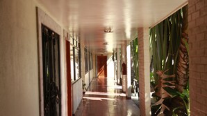 Um corredor com piso de azulejos, portões de metal e paredes de tijolo.