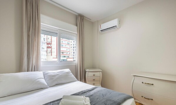 Quarto de hotel com uma cama, mesa de cabeceira, cômoda e ar condicionado.