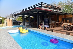 Piscina com brinquedos infláveis, área de estar coberta e bar.