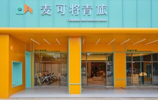 Entrada de hotel com garagem para bicicletas e sinalização de serviço de entrega/coleta de bicicletas.