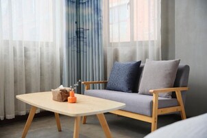 Uma sala de estar moderna com um sofá cinzento, poltronas de madeira e uma pequena mesa com uma caixa de lenços e um recipiente laranja.