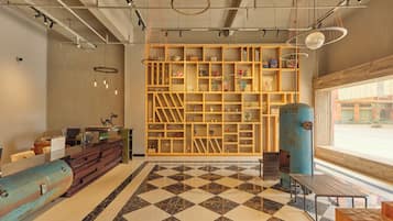 Um interior moderno com chão xadrez, estantes de madeira com diversos objetos, uma mesa com um computador e uma janela grande.