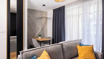 Uma sala de estar moderna com um sofá, uma mesa de jantar e uma luminária pendente.