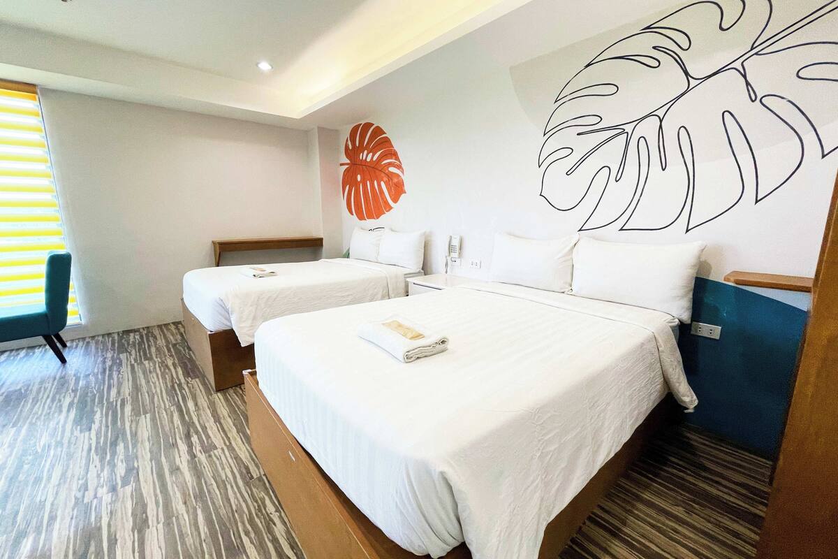 Quarto de hotel com duas camas, um mural grande na parede e piso de madeira.