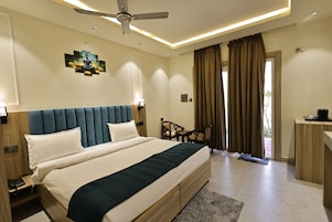 Quarto de hotel com cama, escrivaninha, cadeira e ventilador de teto.
