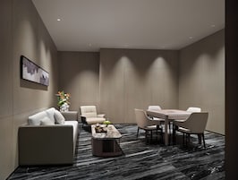 Quarto de hotel moderno com sofá, poltronas, mesa de jantar e mesa de centro.