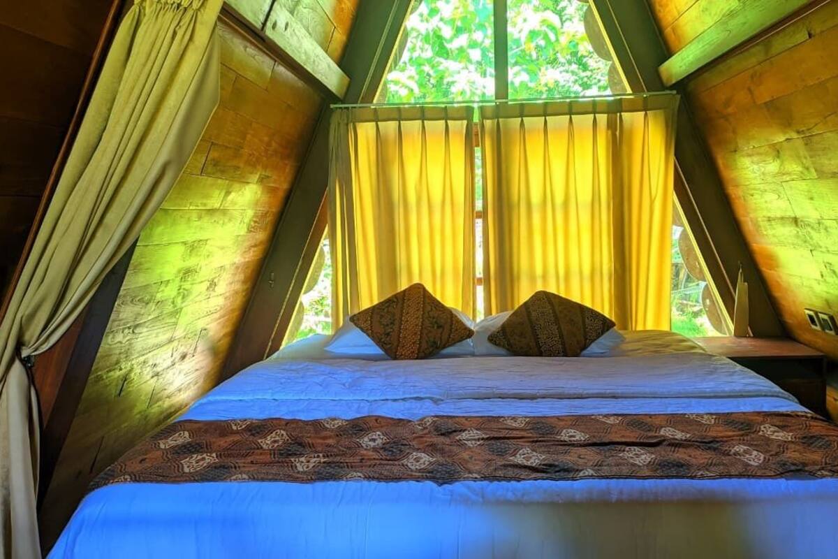 Quarto com cama, cortinas e janela.