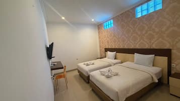Quarto de hotel com duas camas, uma escrivaninha e uma cadeira.