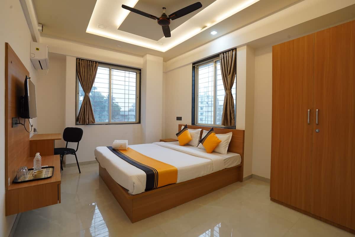 Quarto de hotel moderno com uma cama grande, uma escrivaninha, uma cadeira e um guarda-roupa.