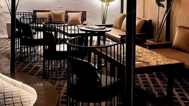 Uma área de estar moderna com disposição em curva, design de teto singular e iluminação ambiente.
