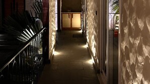 Um corredor com paredes de pedra, uma porta de vidro e uma escada com grades de metal.