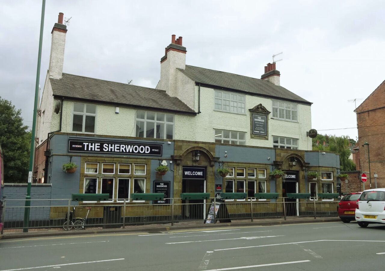 Um edifício de dois andares com uma placa que diz "The Sherwood".