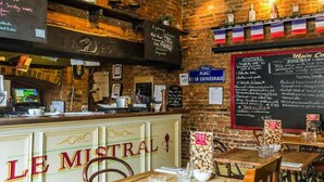 Interior de restaurante com parede de tijolos rústicos, cardápio em lousa e balcão com a inscrição 