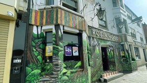 Um edifício com um mural externo colorido retratando uma cena de floresta.