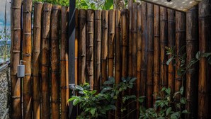 Cercado de bambu com um bebedouro e um portão de metal.