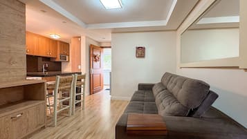 Uma cozinha moderna com armários de madeira, micro-ondas embutido e um espaço de jantar com mesa e cadeiras de madeira.
