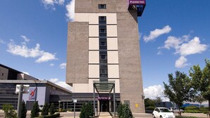Um hotel Premier Inn com design moderno, apresentando uma entrada ampla e um céu claro.