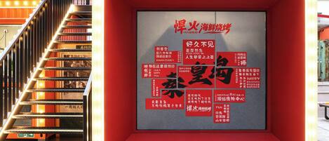 Escadaria com moldura vermelha e placas iluminadas, levando a um patamar com uma grande placa vermelha com caracteres chineses.