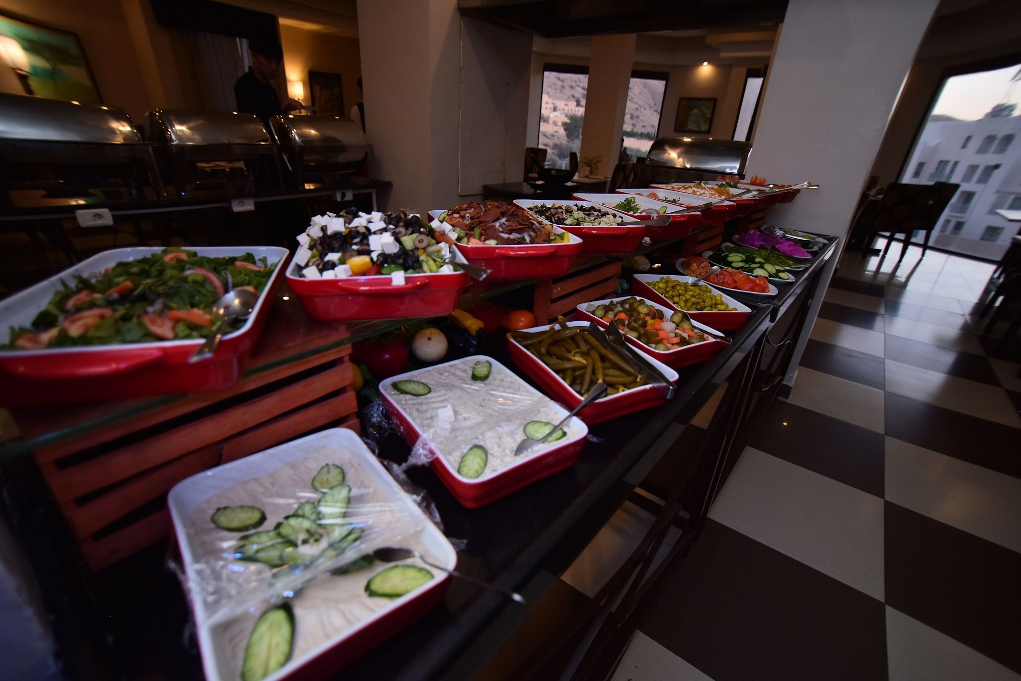 Buffet com diversas opções de comida, incluindo saladas, frutas e legumes.