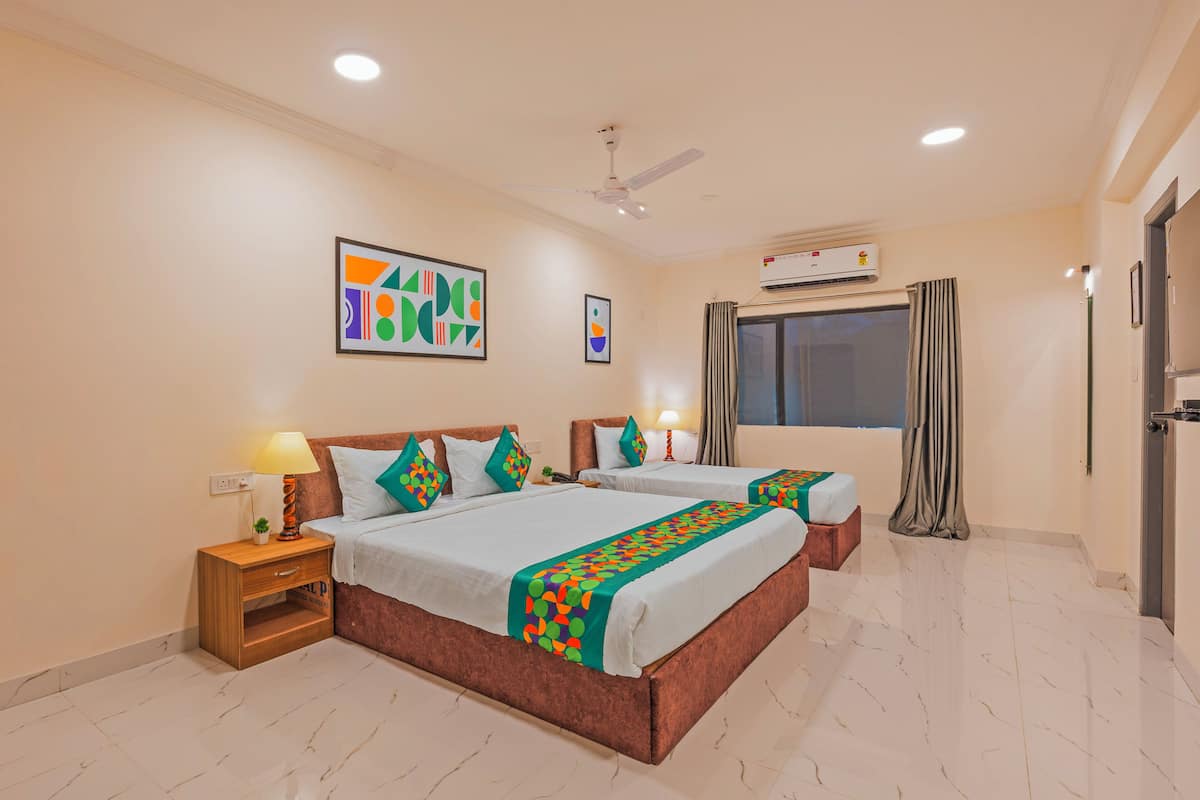 Quarto de hotel com duas camas, ventilador de teto, ar condicionado e janela com cortinas.