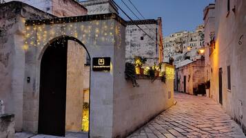Uma rua de paralelepípedos estreita com um edifício apresentando uma entrada em arco e luzes de cordão.
