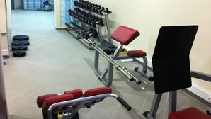 Uma academia com equipamentos de musculação, bancos e halteres.