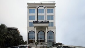 Hotel Clubhouse com design arquitetônico clássico, apresentando grandes janelas em arco e uma entrada imponente.