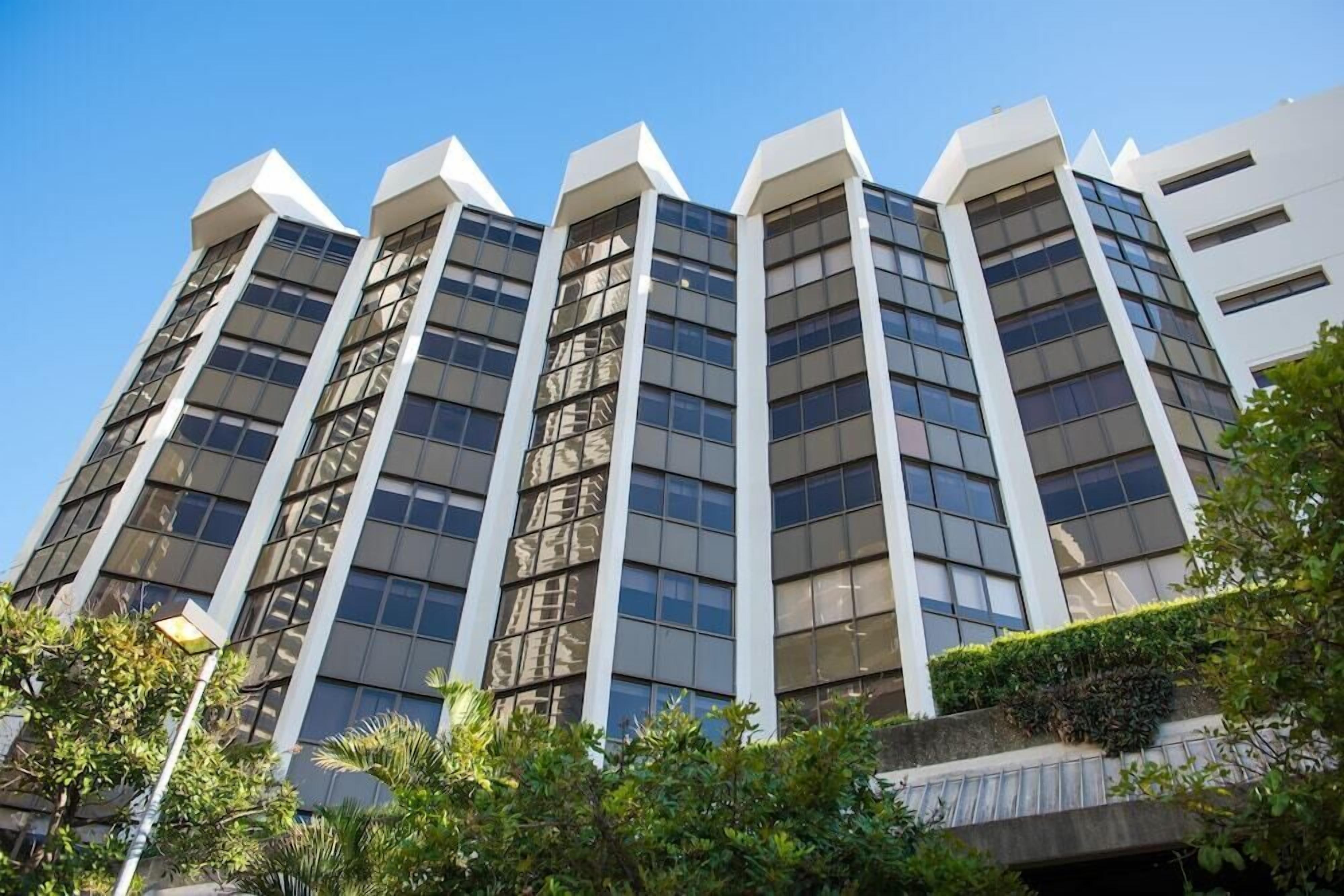 Um edifício moderno de vários andares, com fachada simétrica, janelas amplas e telhado plano.