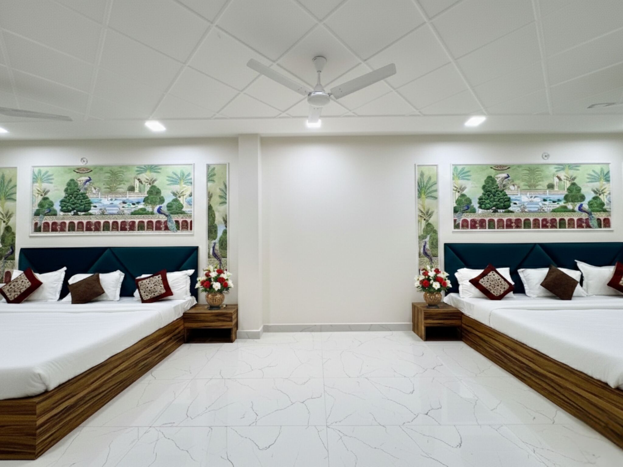 Quarto de hotel com duas camas, um ventilador de teto, obras de arte nas paredes e piso de mármore.