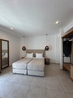 Cama de casal com duas almofadas, mesa de cabeceira pequena, espelho e guarda-roupa.