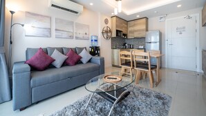 Uma sala de estar moderna com um sofá cinzento, uma mesa de centro de vidro e um tapete macio.